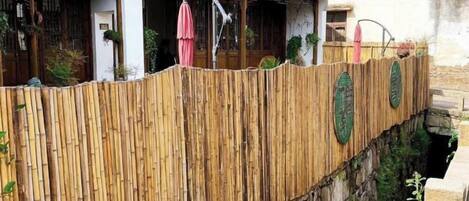 Um edifício tradicional com cerca de bambu, portas de madeira e telhado de telhas.