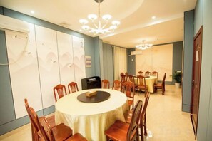 Uma sala de jantar com mesa redonda, cadeiras e um lustre.