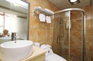Casa de banho com lavatório branco, sanita e cabine de duche com vidro.