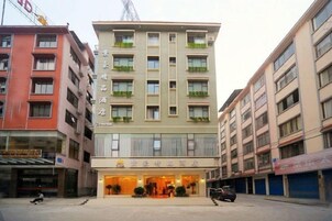 Um hotel de vários andares com entrada central, varandas e estacionamento.