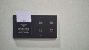 Painel de controlo preto fixado na parede, com leitor de cartão contactless e identificação em caracteres chineses.