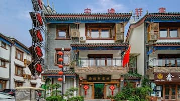 Um edifício tradicional com vários andares, varandas e uma placa com caracteres chineses.