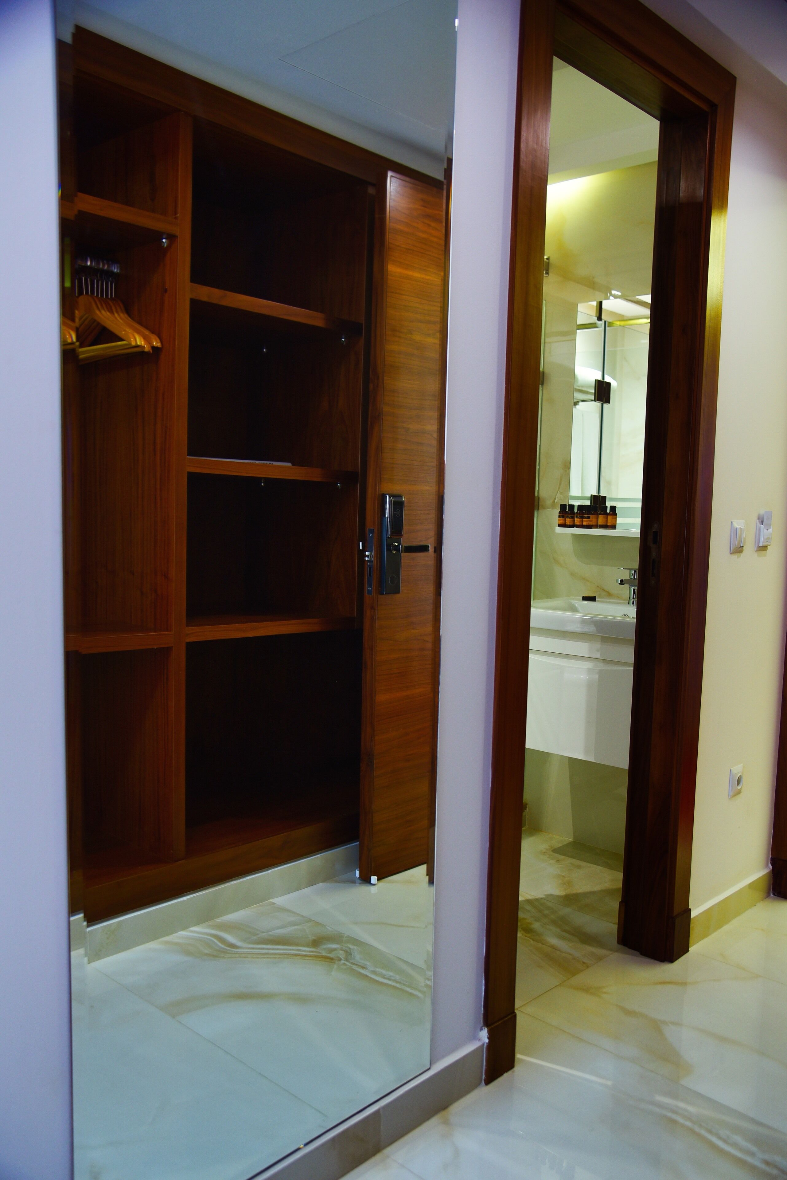 Quarto com guarda-roupa de madeira, banheiro com pia e espelho, e piso revestido de azulejos.