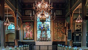 Um interior ornamentado com um lustre central, janelas de vitrais e um design simétrico.