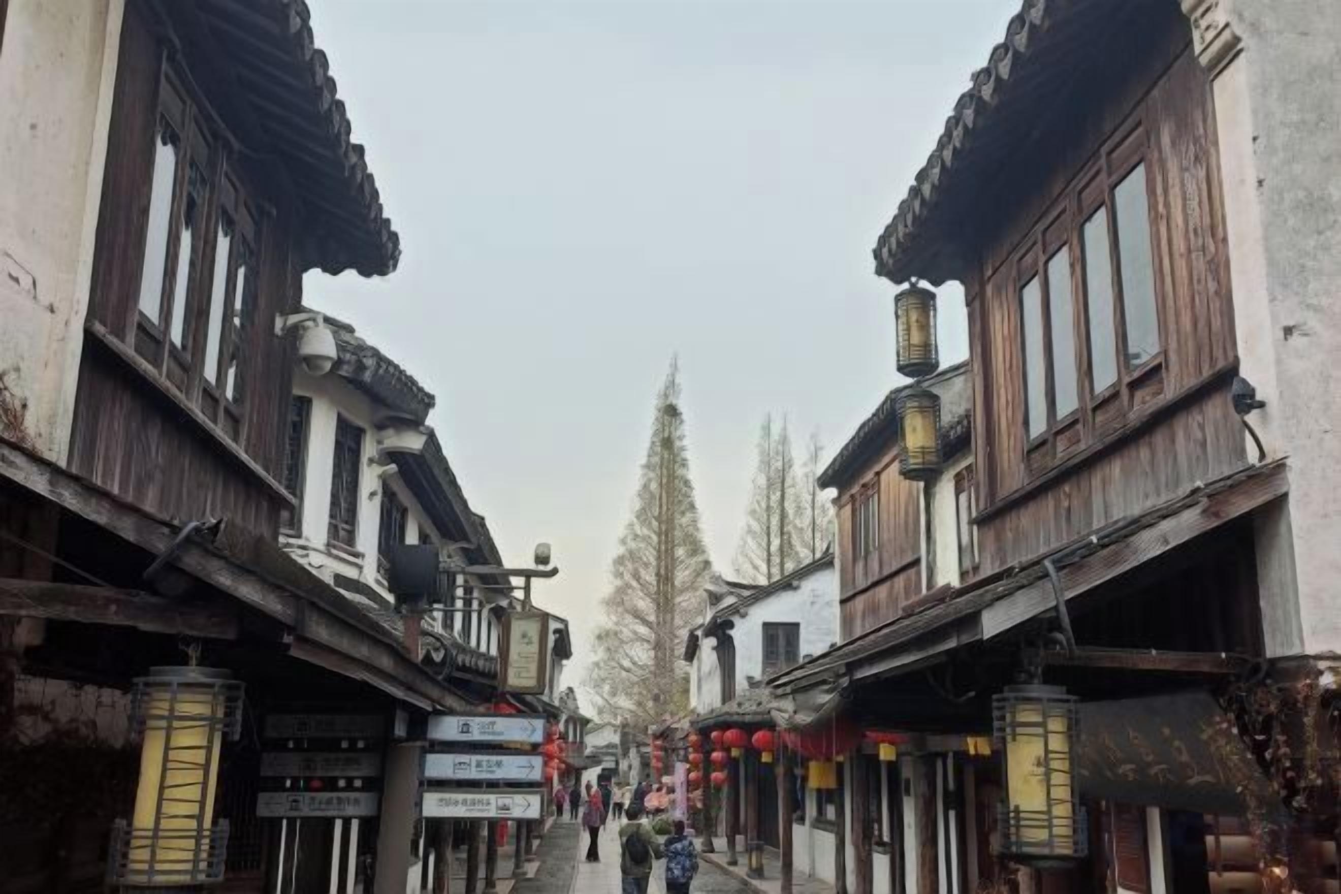 Uma rua estreita com edifícios de madeira tradicionais, lanternas e placas indicando estabelecimentos locais.