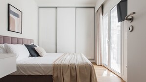 Quarto com cama, mesa de cabeceira, janela e porta deslizante.