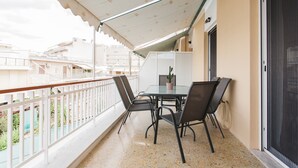 Varanda com mesa e cadeiras de vidro, uma planta em vaso e uma porta de correr.