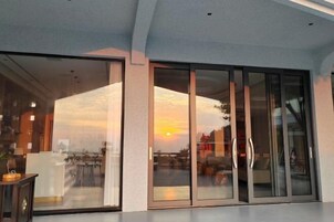 Um edifício moderno com amplas portas e janelas de vidro, refletindo o pôr do sol.