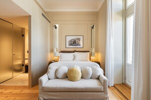 Quarto bem organizado com cama, abajures e um quadro na parede.