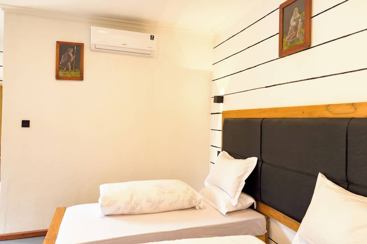 Quarto de hotel com cama, cabeceira, ar condicionado fixado na parede e um quadro emoldurado.