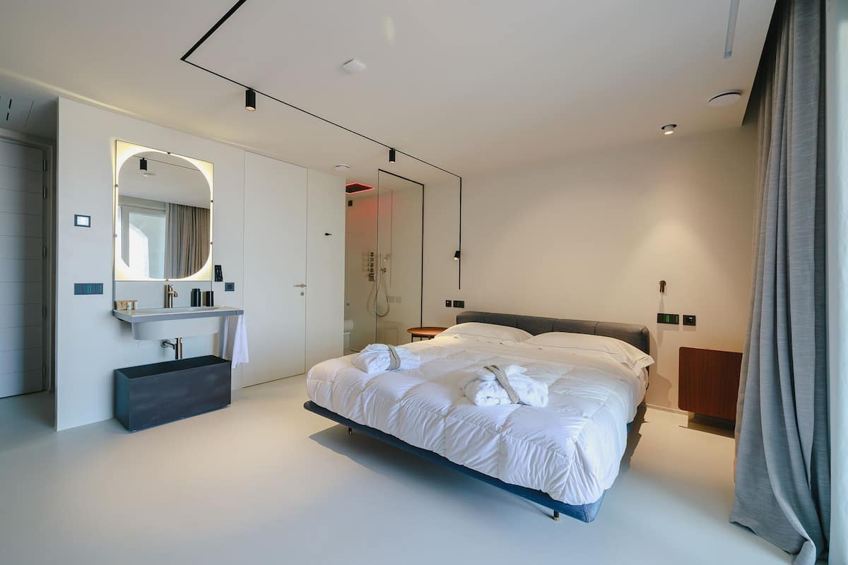 Quarto de hotel moderno com uma cama grande, toucador embutido e área de chuveiro.