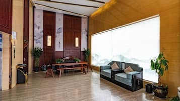 Quarto espaçoso com piso de madeira, um sofá, uma mesa de madeira e uma janela grande.