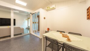 Um quarto moderno e bem iluminado com uma mesa de jantar, cadeiras e um sofá.