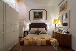 Quarto com uma cama grande, penteadeira, mesa de cabeceira e um quadro na parede.