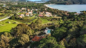 Vista aérea de uma área residencial costeira com casas, piscina e praia.