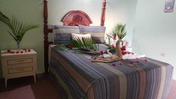 Quarto com cama, mesa de cabeceira e painel de cabeceira fixado na parede.