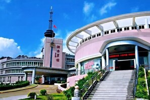 Um edifício moderno com uma torre imponente, uma entrada curva e uma escadaria que leva à entrada principal.