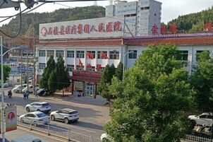 Um edifício com uma placa indicando ser uma clínica médica. Há bandeiras expostas na fachada e vários carros estacionados em frente.