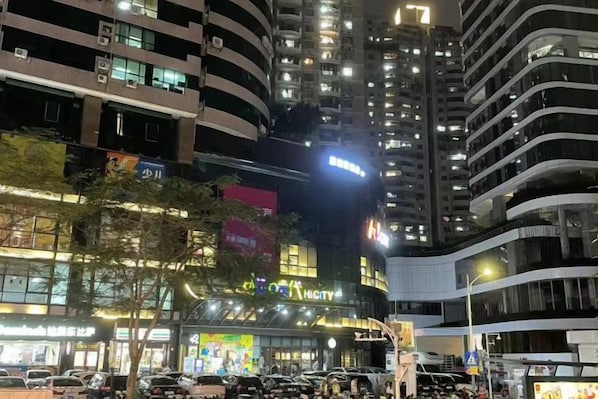 Um edifício alto com vários andares, janelas iluminadas e uma placa visível de uma loja chamada 'HicCity'.