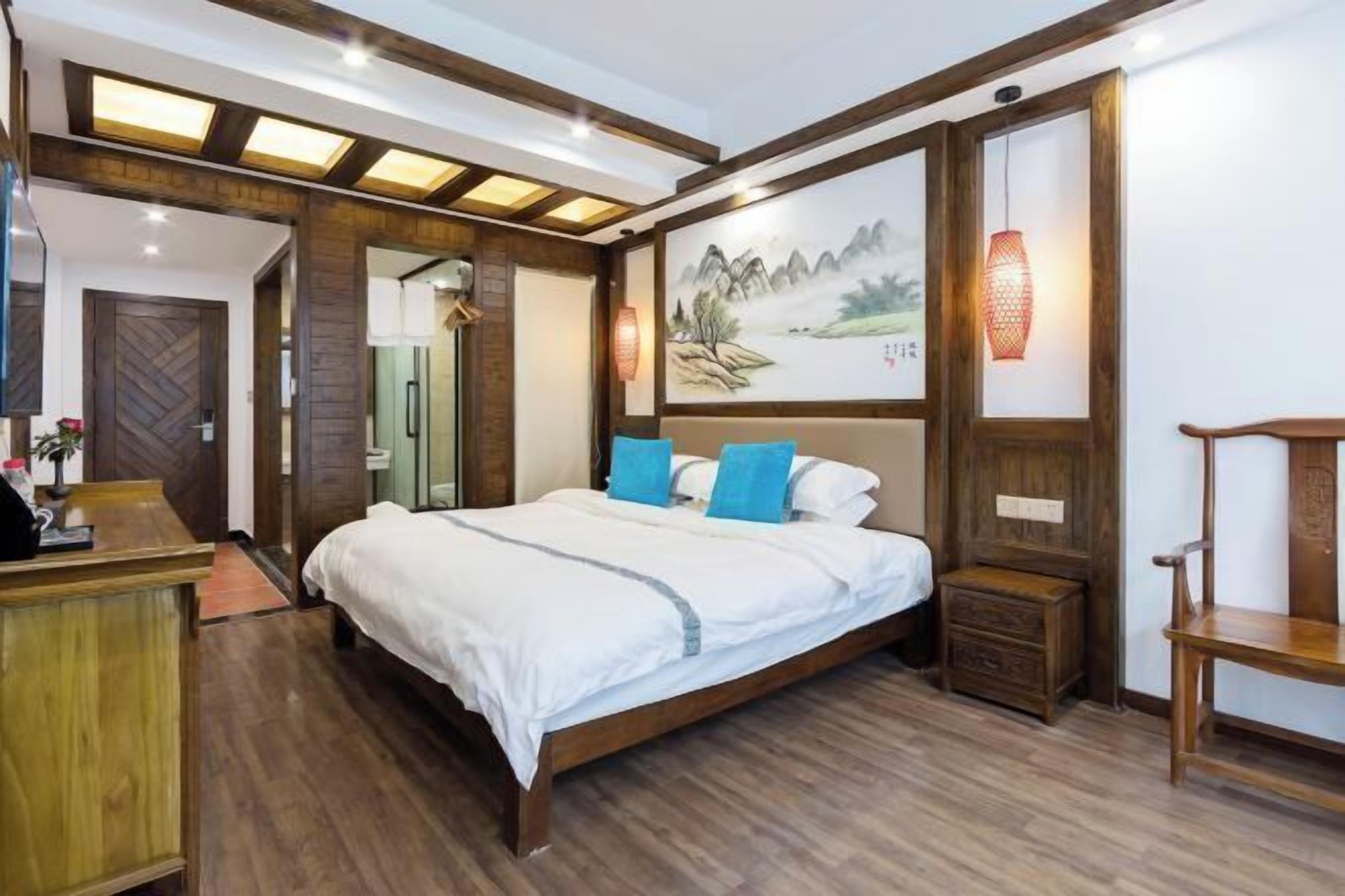 Quarto de hotel com uma cama grande, cabeceira de madeira, uma escrivaninha e uma mesa de cabeceira.