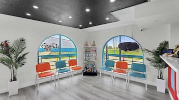 Uma área de recepção com design moderno, com balcão de atendimento, espaço de estar com cadeiras e vista através de amplas janelas.