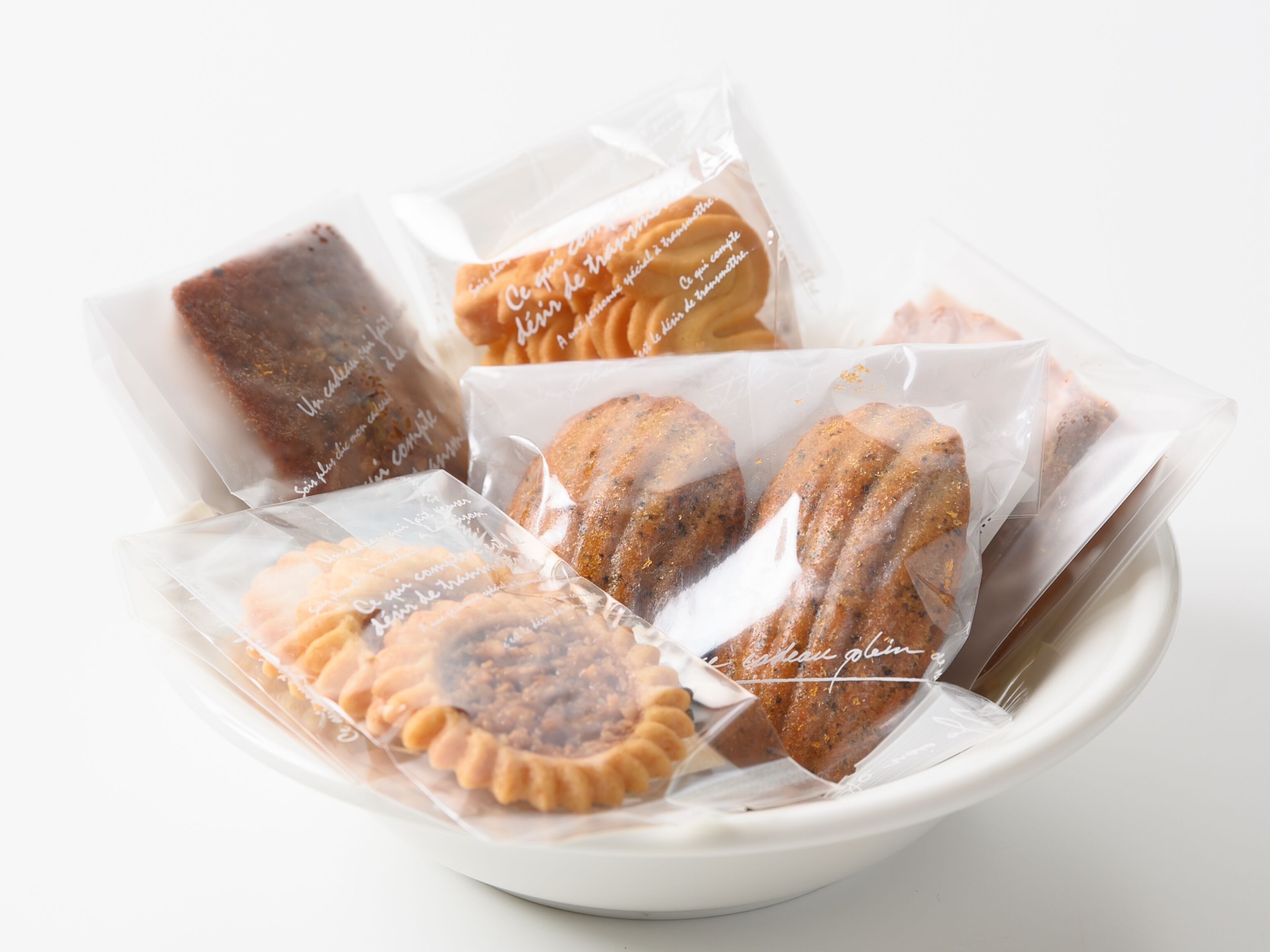 Uma tigela branca com diversos produtos de pastelaria embalados.