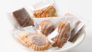 Uma tigela branca com diversos produtos de pastelaria embalados.