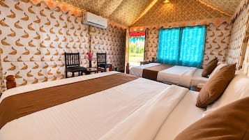 Quarto de hotel com duas camas, ventoinha no teto e papel de parede estampado.