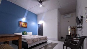 Quarto com cama, mesa de madeira, cadeira e parede azul decorativa.