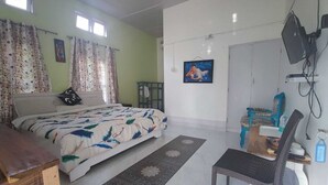 Quarto com cama, escrivaninha, cadeira, televisão e um quadro na parede.