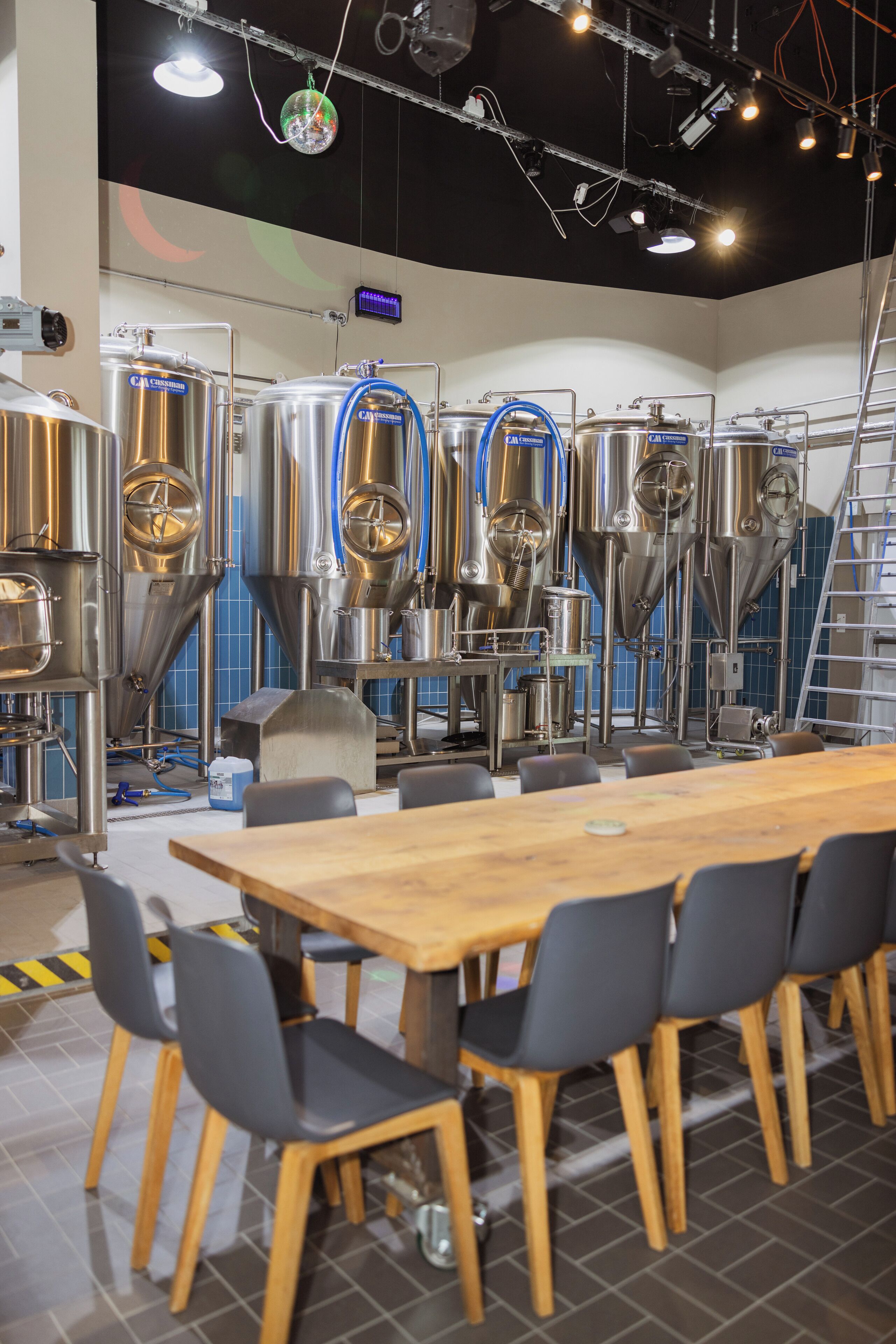 Cozinha moderna com eletrodomésticos de aço inoxidável, uma mesa de madeira e cadeiras pretas.