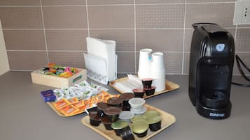 Um espaço com café, incluindo cafeteira, xícaras e diversos alimentos sobre um balcão.