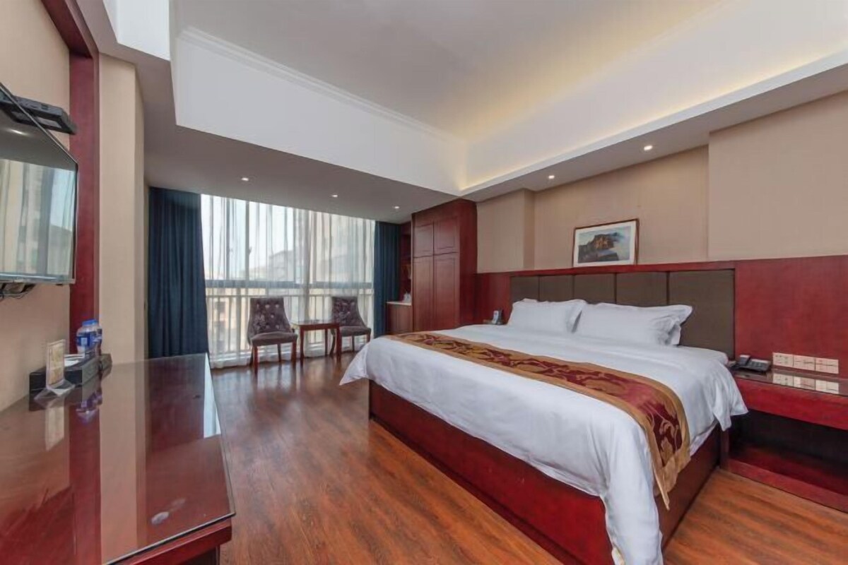 Quarto de hotel com uma cama grande, uma escrivaninha e uma cadeira.
