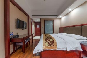 Quarto de hotel com cama, escrivaninha, televisão e porta que dá para outro aposento.