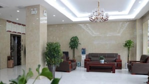 Um lobby moderno com teto alto, iluminação embutida, um candelabro e área de estar com sofás e mesa de centro.