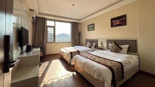 Quarto de hotel com duas camas, uma escrivaninha, uma televisão e uma janela com vista.