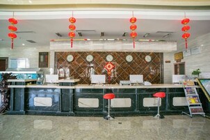 Uma área de recepção com balcão, cadeiras e um painel decorativo.