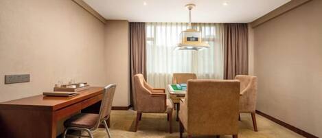 Quarto de hotel com uma mesa de jantar, quatro cadeiras, uma escrivaninha e um candelabro.