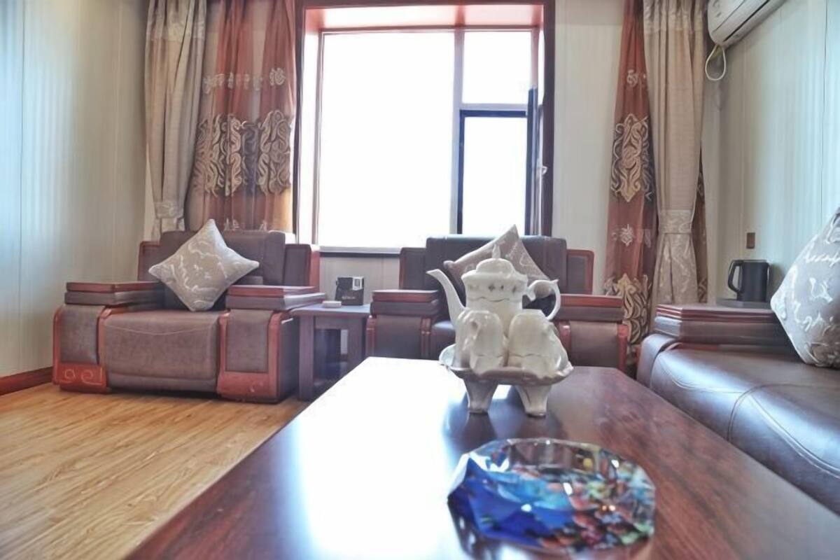 Uma sala de estar com sofá, mesa de centro e janela com cortinas.