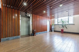 Um hall espaçoso com painéis de madeira, um balcão de recepção e um vaso de plantas.
