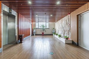 Um corredor com piso de madeira, uma planta em vaso e uma prateleira na parede.