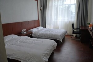 Quarto de hotel com duas camas, uma escrivaninha e uma cadeira.