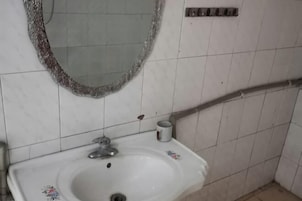 Uma casa de banho com uma pia branca, um espelho e uma barra de toalhas.