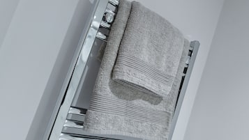 Uma casa de banho com um porta-toalhas branco com duas toalhas dobradas.