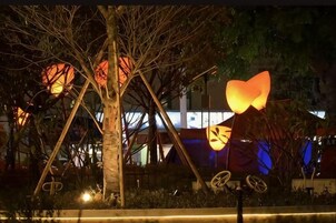 Uma árvore com um poste de luz e uma decoração luminosa em formato de coração.
