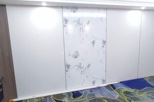 Quarto com um armário grande de cor branca com padrão marmorizado, um tapete estampado em azul e um piso de madeira.