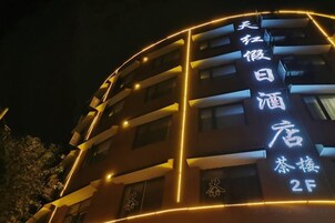 Um edifício de vários andares com letreiros iluminados em escrita estrangeira, provavelmente indicando um hotel ou propriedade comercial.