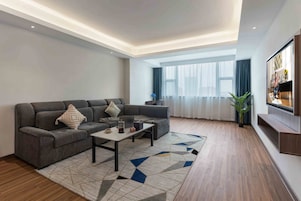 Uma sala de estar moderna com um sofá seccional, uma mesa de centro e uma janela grande com cortinas.