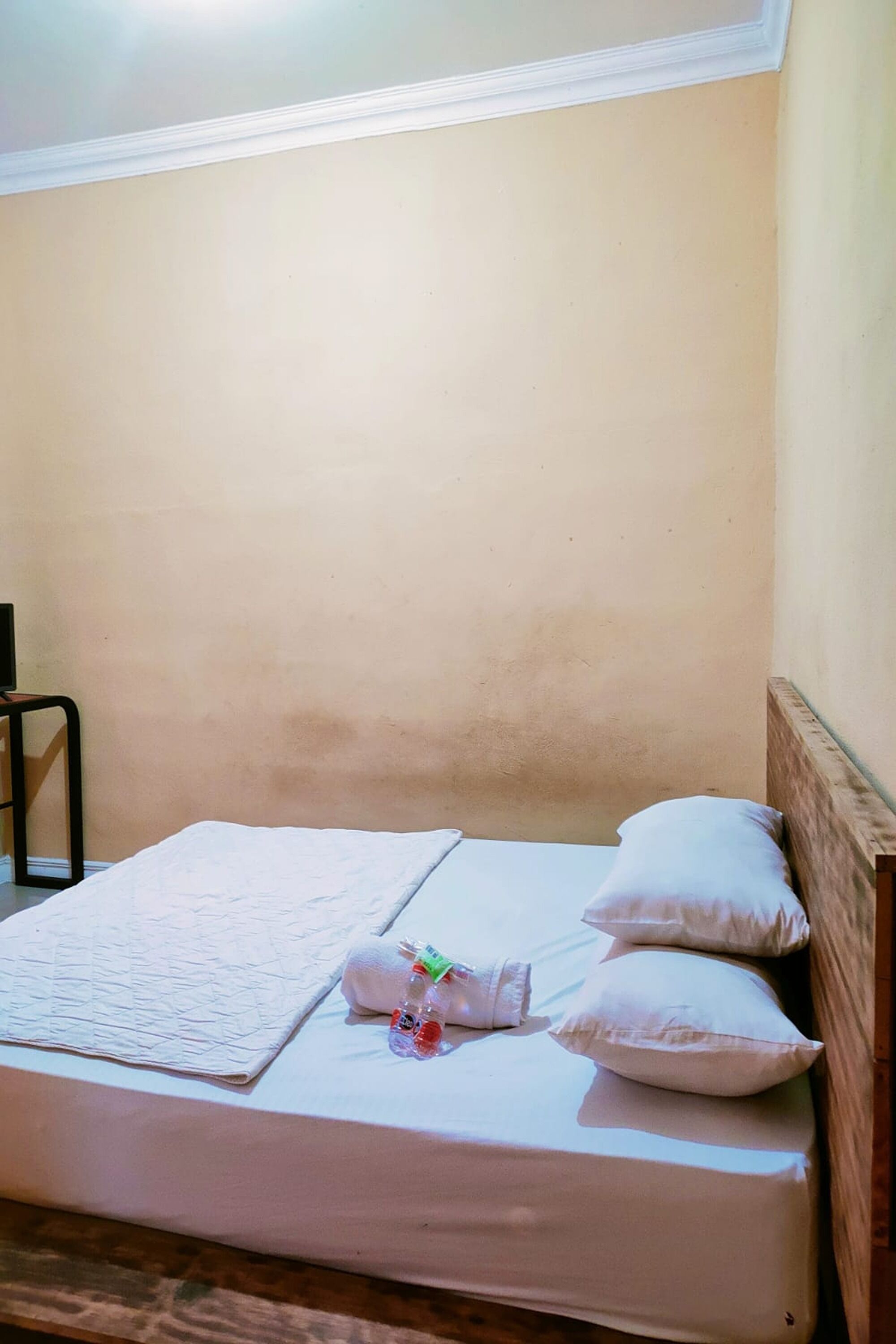 Uma cama de solteiro com colchão branco, duas almofadas e um cobertor.
