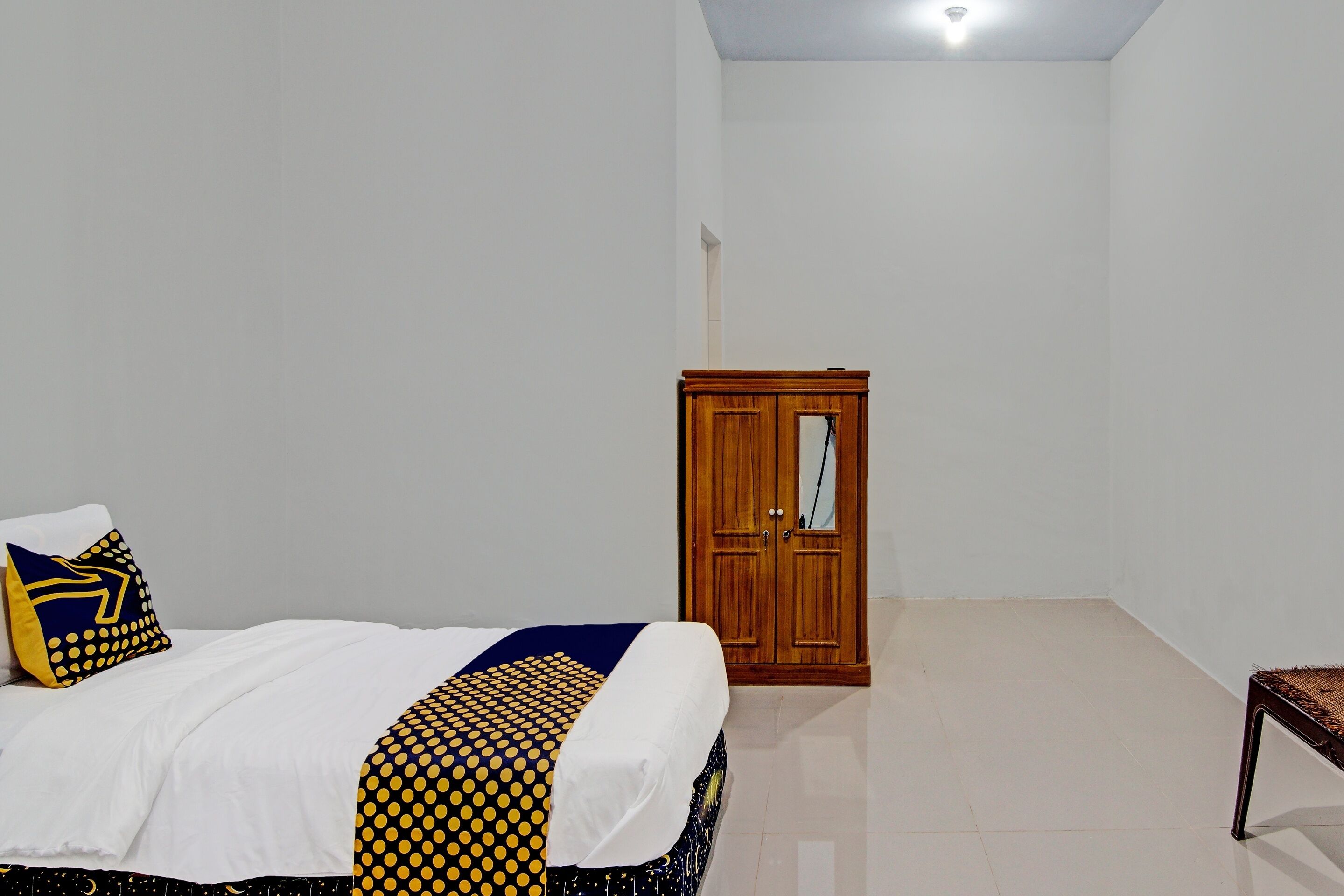 Quarto com cama, guarda-roupa e um banquinho.